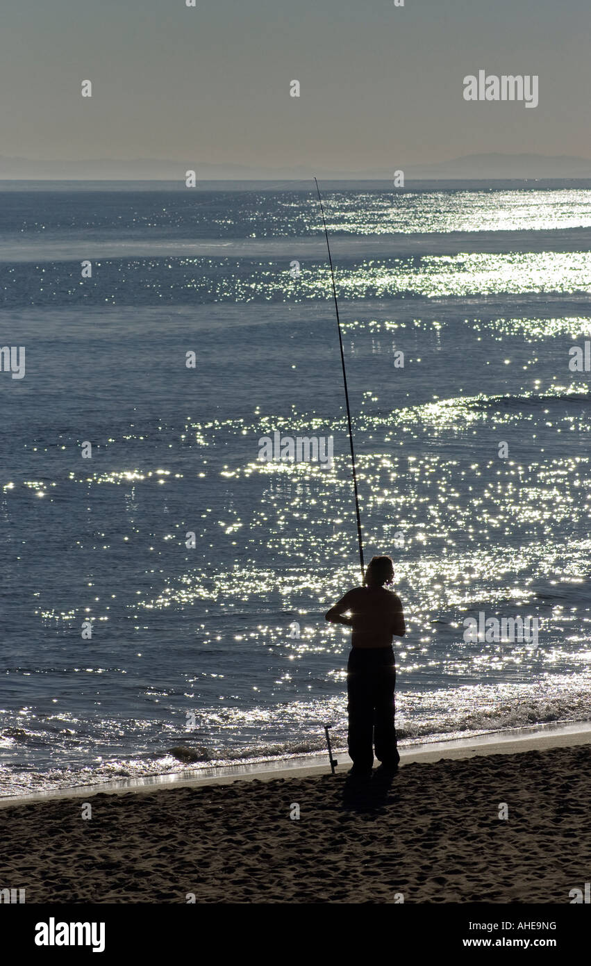 Fisherman, in silhouette, fishing from a Spanish beach Stock Photo - Alamy