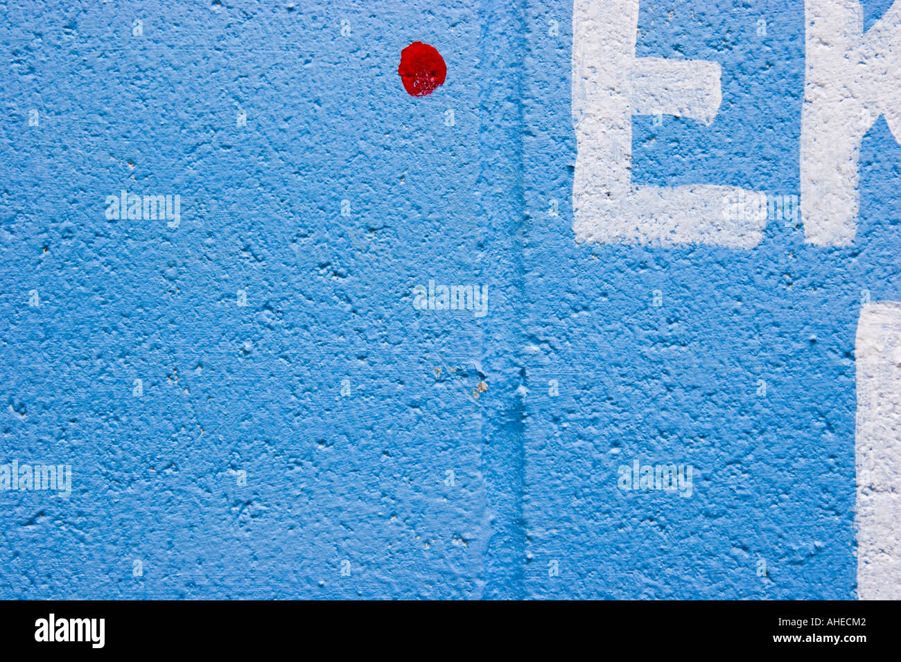 red dot on blue block wall with writing Stock Photo - Alamy