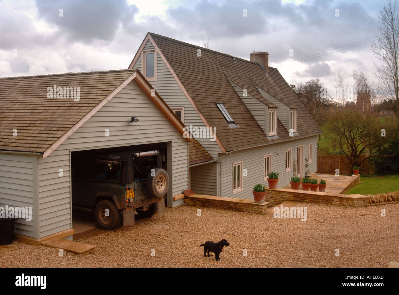 A TIMBER FRAMED HOUSE WITH A BLACK TERRIER DOG ON THE DRIVEWAY Stock ...