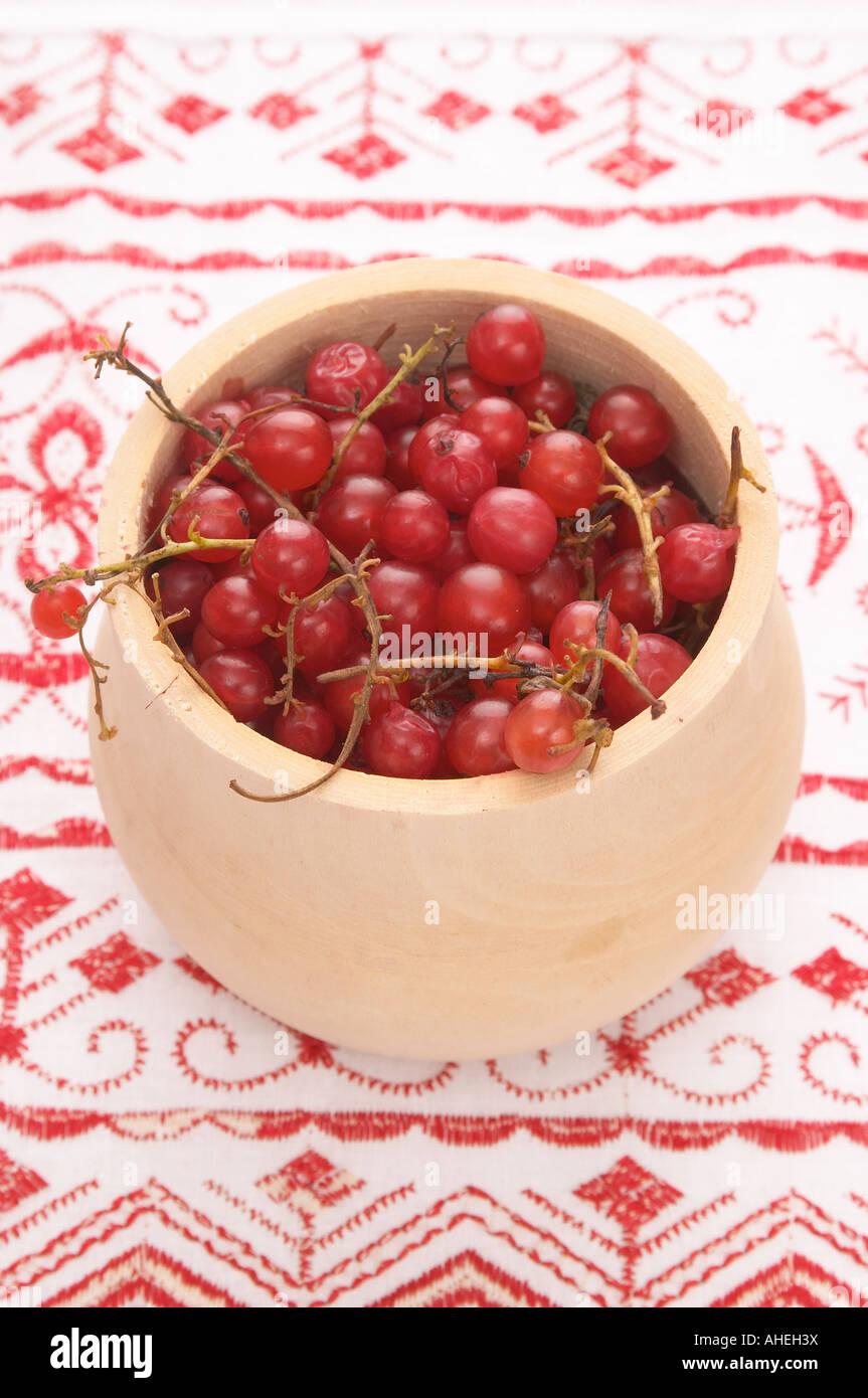 Stylish red currant in light wood cup on the traditional cover with ...