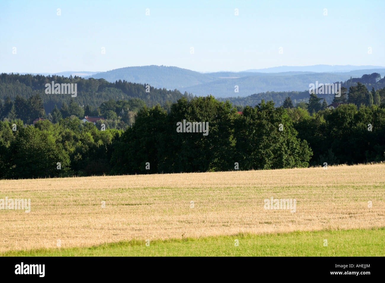 A scenic rural landscape with green forests, distant hills, and a ...