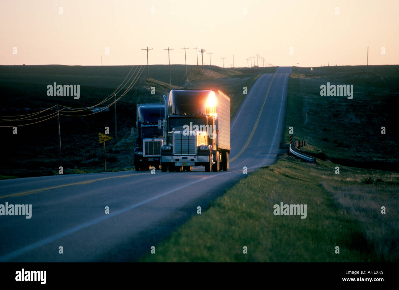 One semi truck overtakes another on a two lane highway a dusk Stock ...