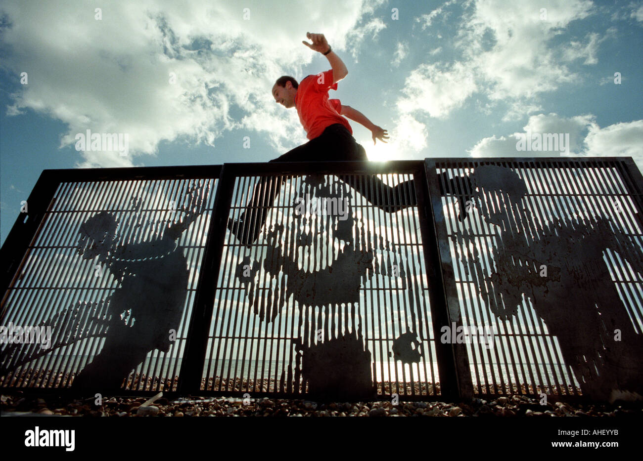 Sculptor Bruce Williams leaps over three of his laser cut panels for a ...