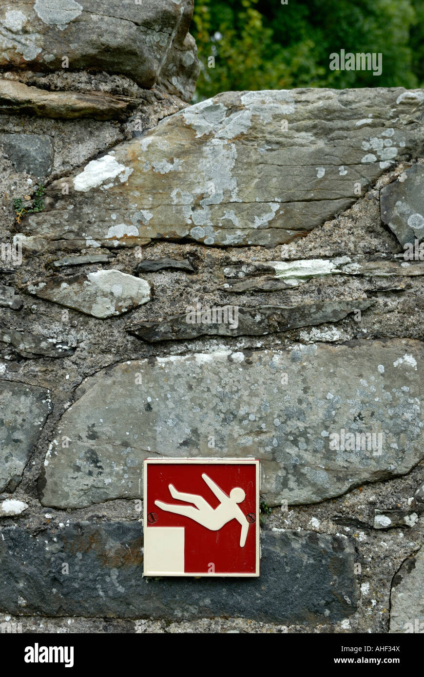 Falling person safety warning sign on old stone wall Stock Photo - Alamy