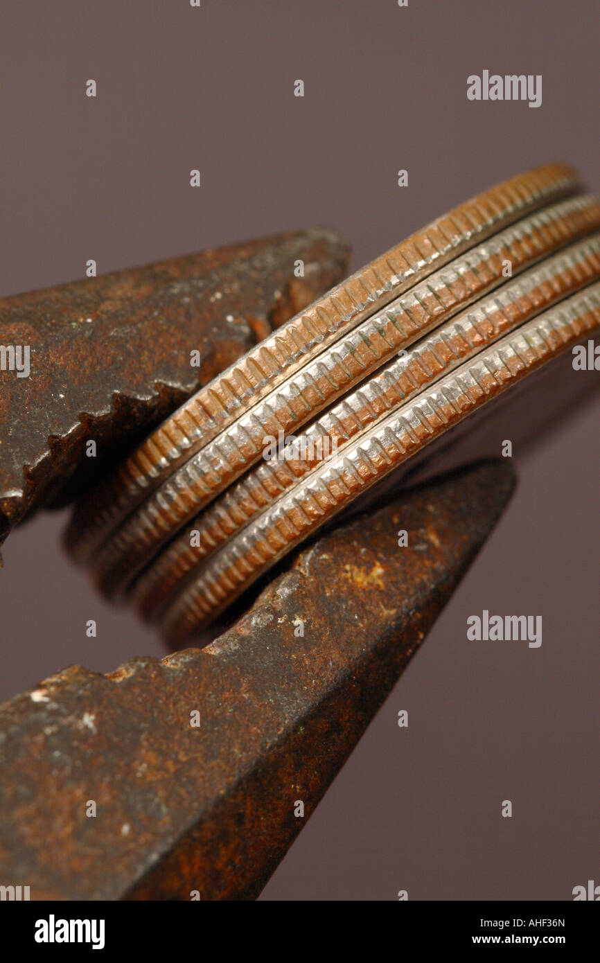 Coins money being squeezed pressure from plier tool Stock Photo - Alamy