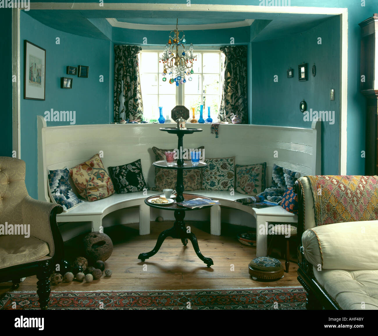 White painted settle with blue cushions and three tiered table in green ...