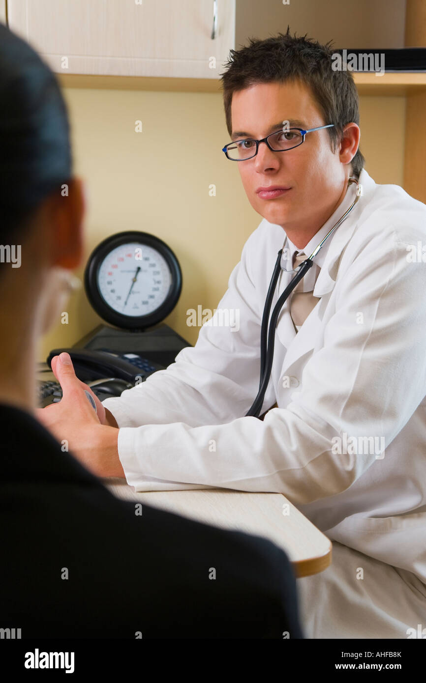 A female patient in consultation with a male doctor visible behind him ...