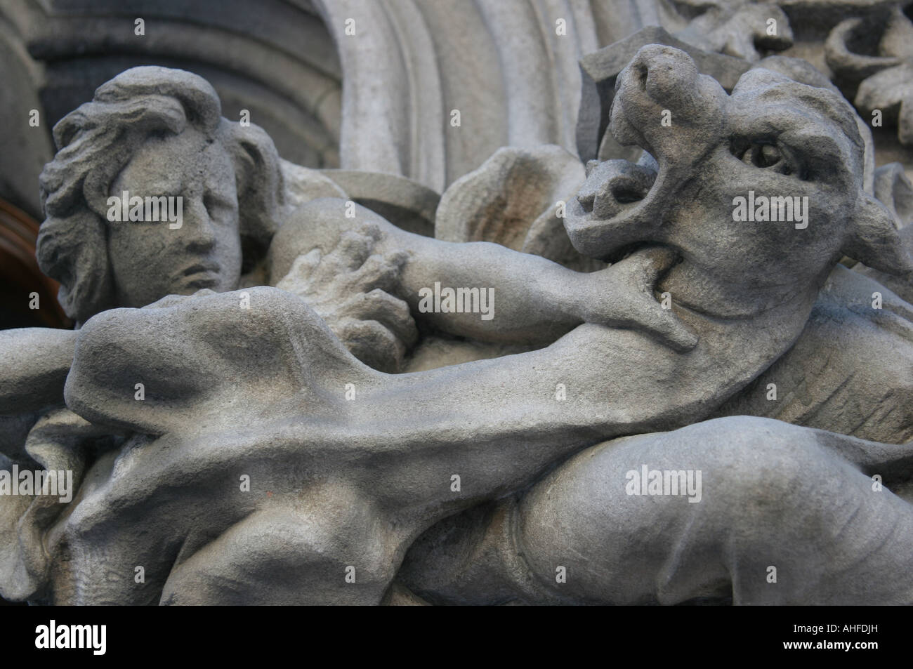 Gargoul of a maiden fighting a dra on a historical building in ...