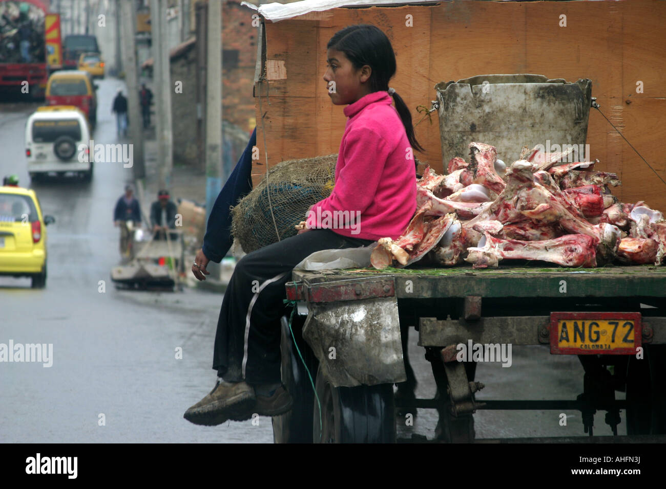 A girl sitting on a lorry carrying bones of animals in a street of ...