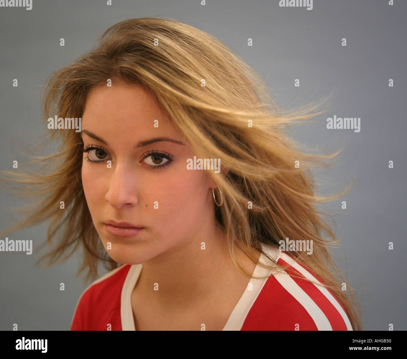 A beautiful blond teenage girl with long wind blown hair in a tight ...