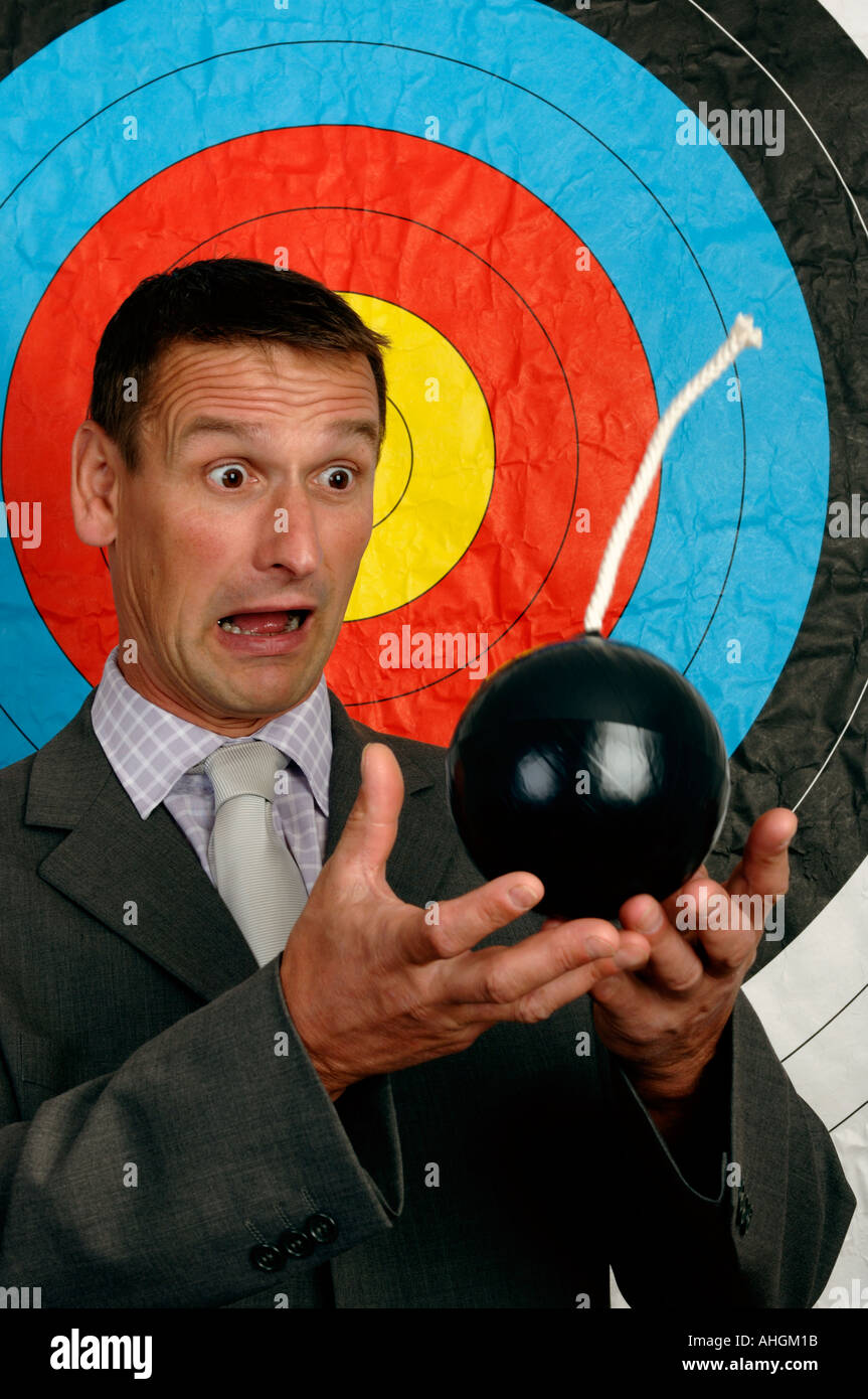 Businessman holding a round bomb in front of a target Stock Photo - Alamy