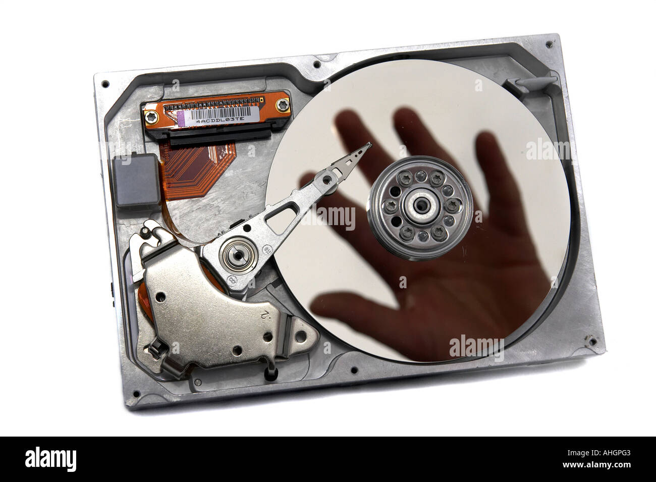 hand reflected in disc of open broken hard drive against white ...