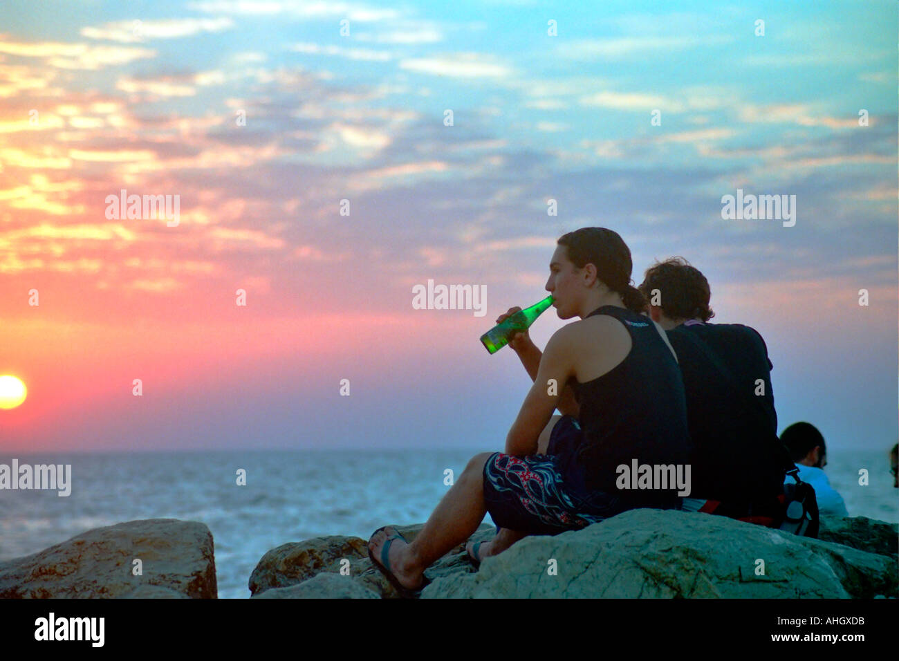 two young adults drinking beer during sun set Stock Photo - Alamy