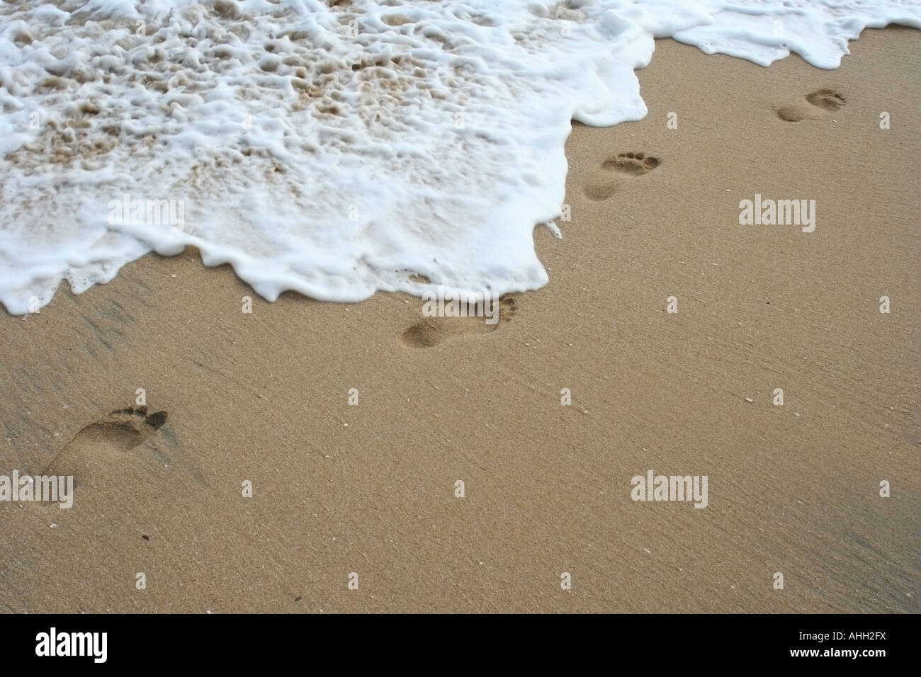 Footprints on the beach with foam Stock Photo - Alamy