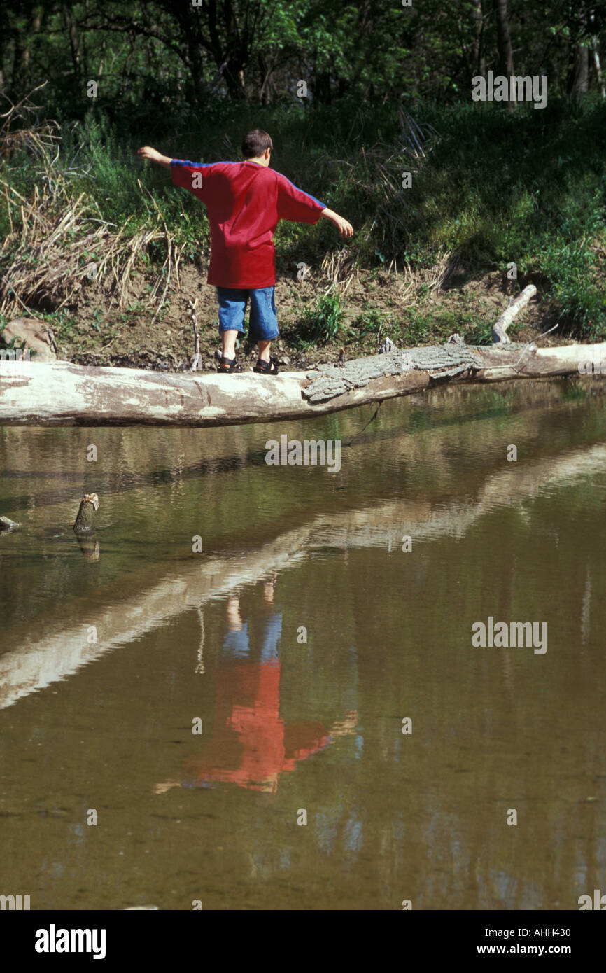 Boy crossing Creek on Log Stock Photo - Alamy