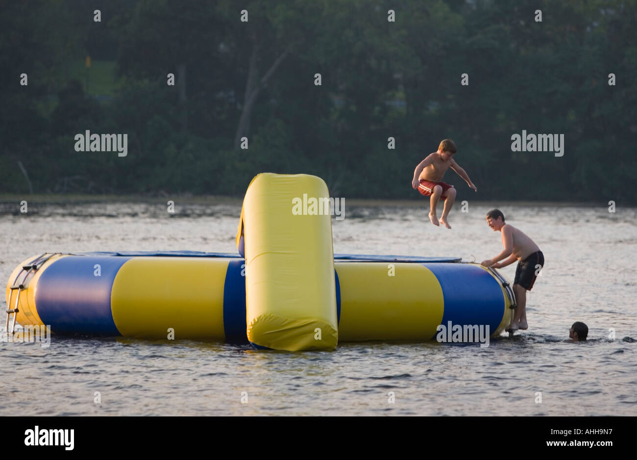 Boys playing on an inflatable raft on a lake Stock Photo - Alamy