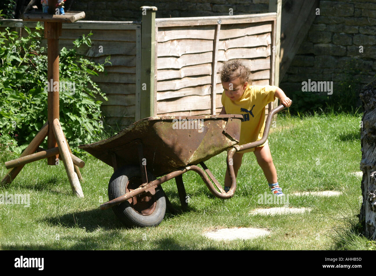 A small boy struggling to push a large and heavy wheelbarrow Stock ...