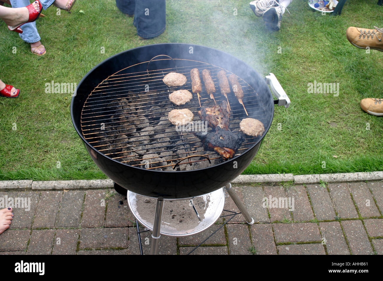 Barbeque with feet of party guests all around the edge of the frame ...
