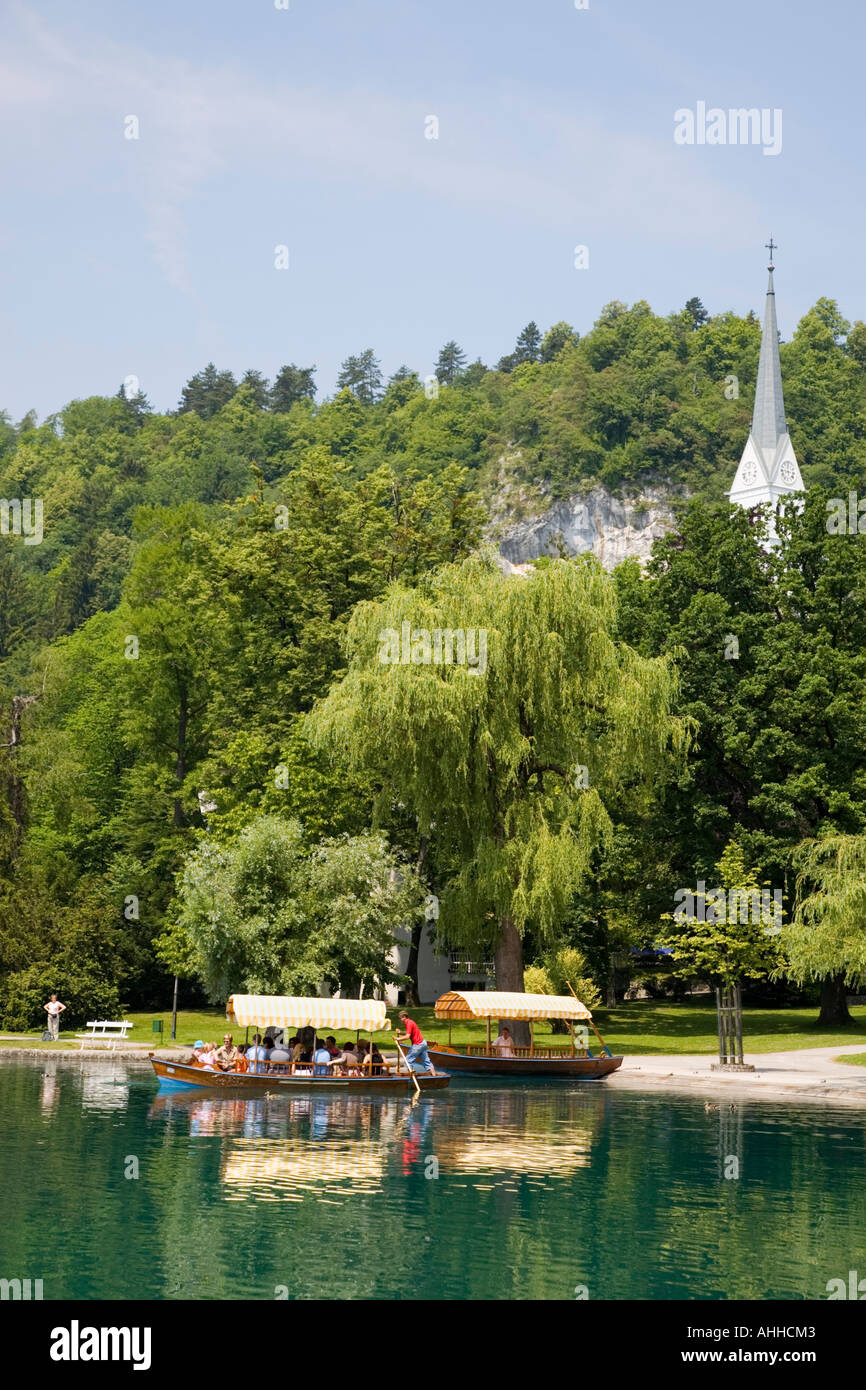 Lake Bled in summer with traditional wooden pletnja rowing boats moored ...