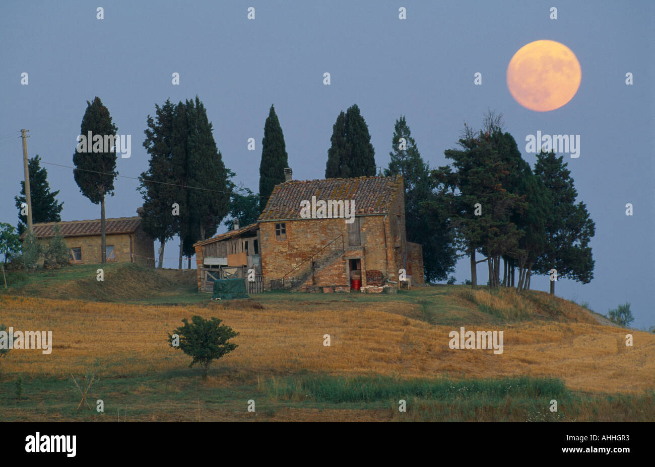 ITALY Tuscany Full moon in evening sky over farmhouse and cypress trees ...