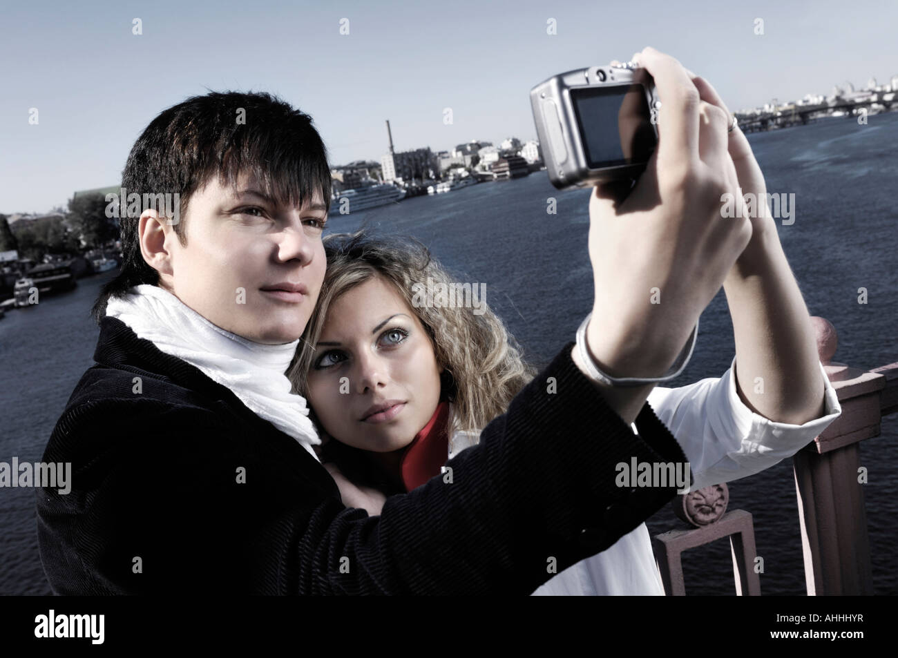 Young man an a young woman on the bridge taking pictures of themselves ...