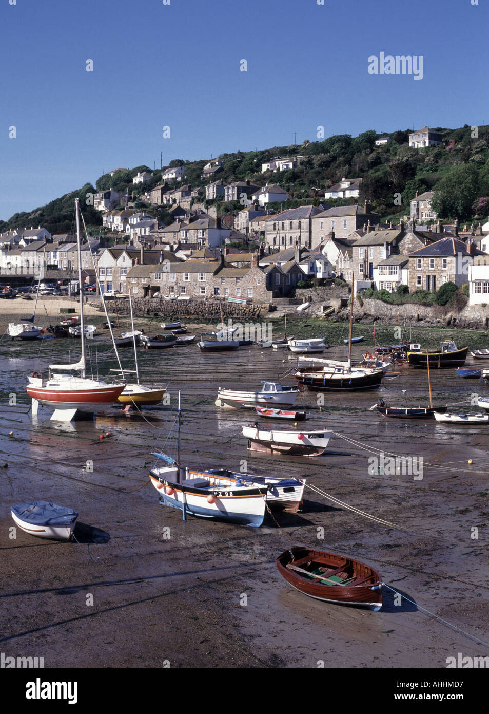 Mousehole harbour at low tide with village beyond Stock Photo - Alamy