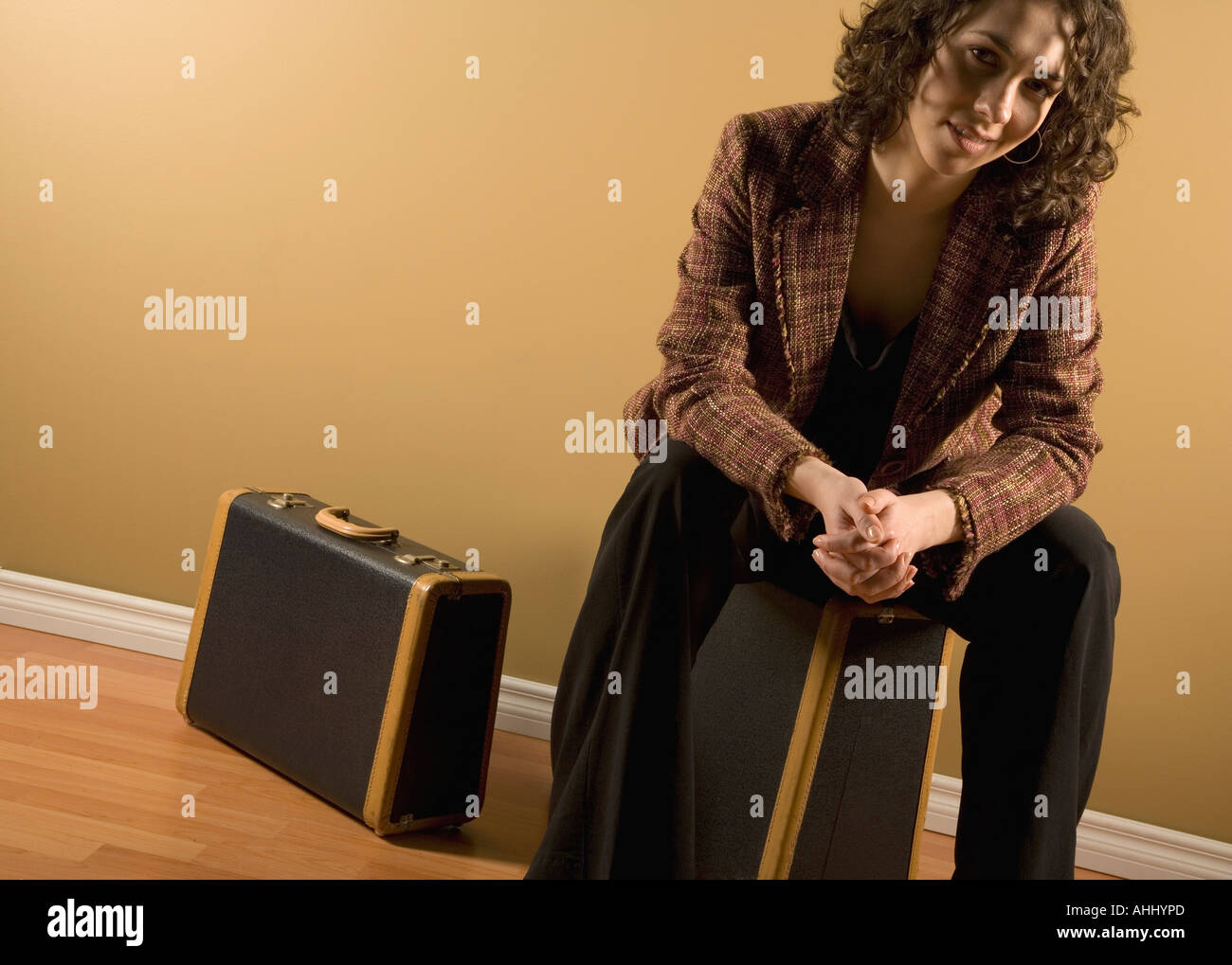 Woman sitting on suitcase Stock Photo - Alamy
