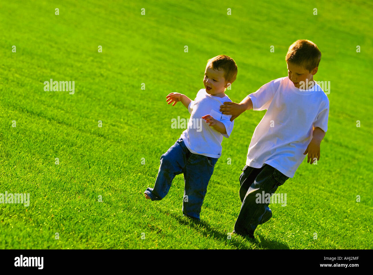 Little boys running across a stretch of grass Stock Photo - Alamy