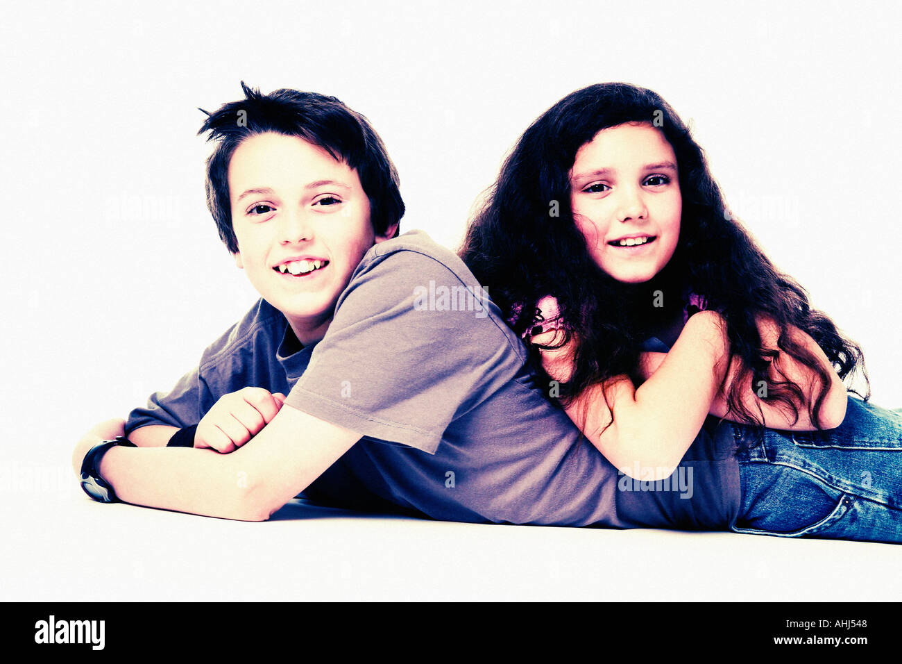 Boy laying on floor with girl lying across his back both smiling at ...