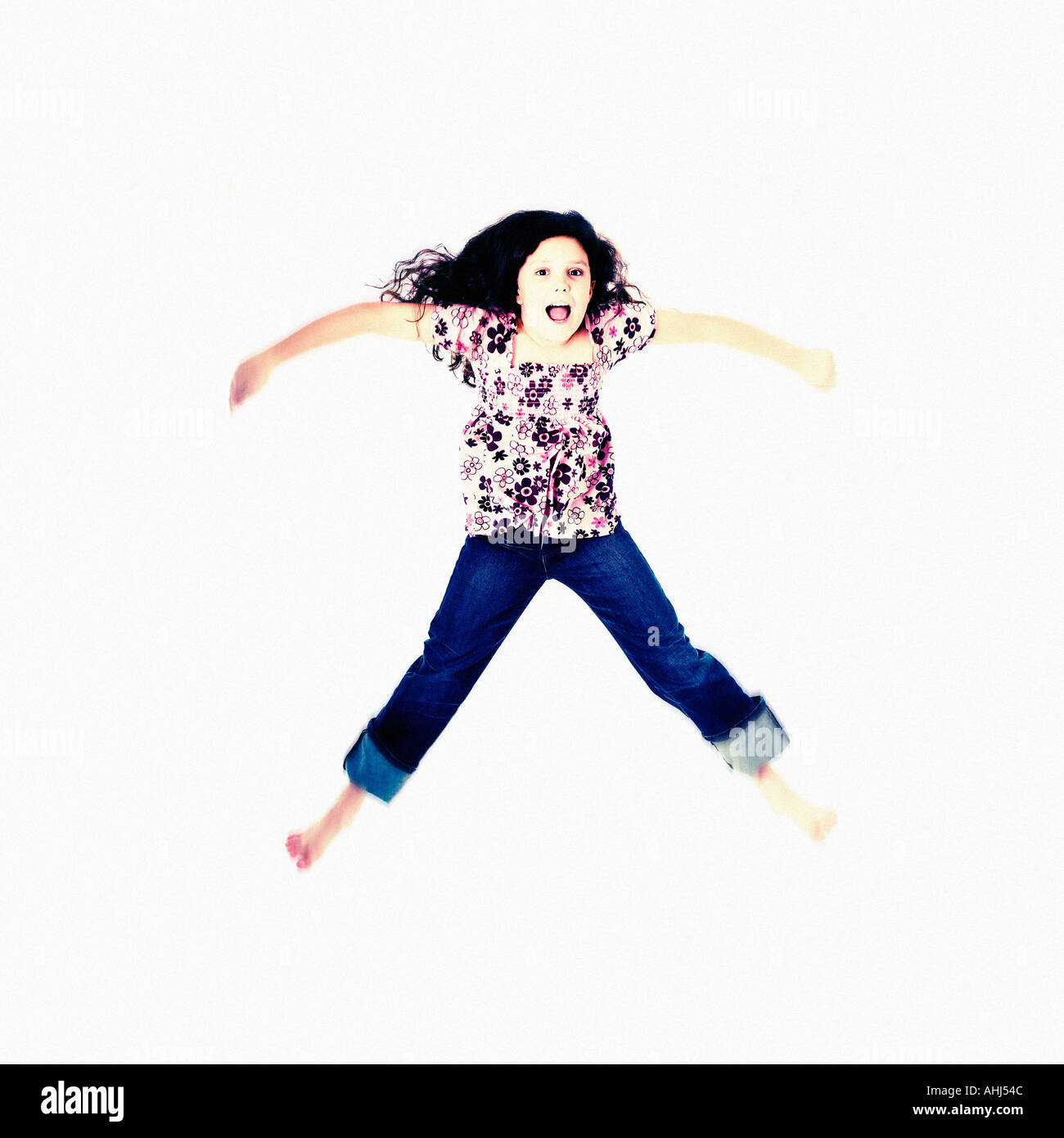 Girl doing star jump in air against white background Stock Photo - Alamy