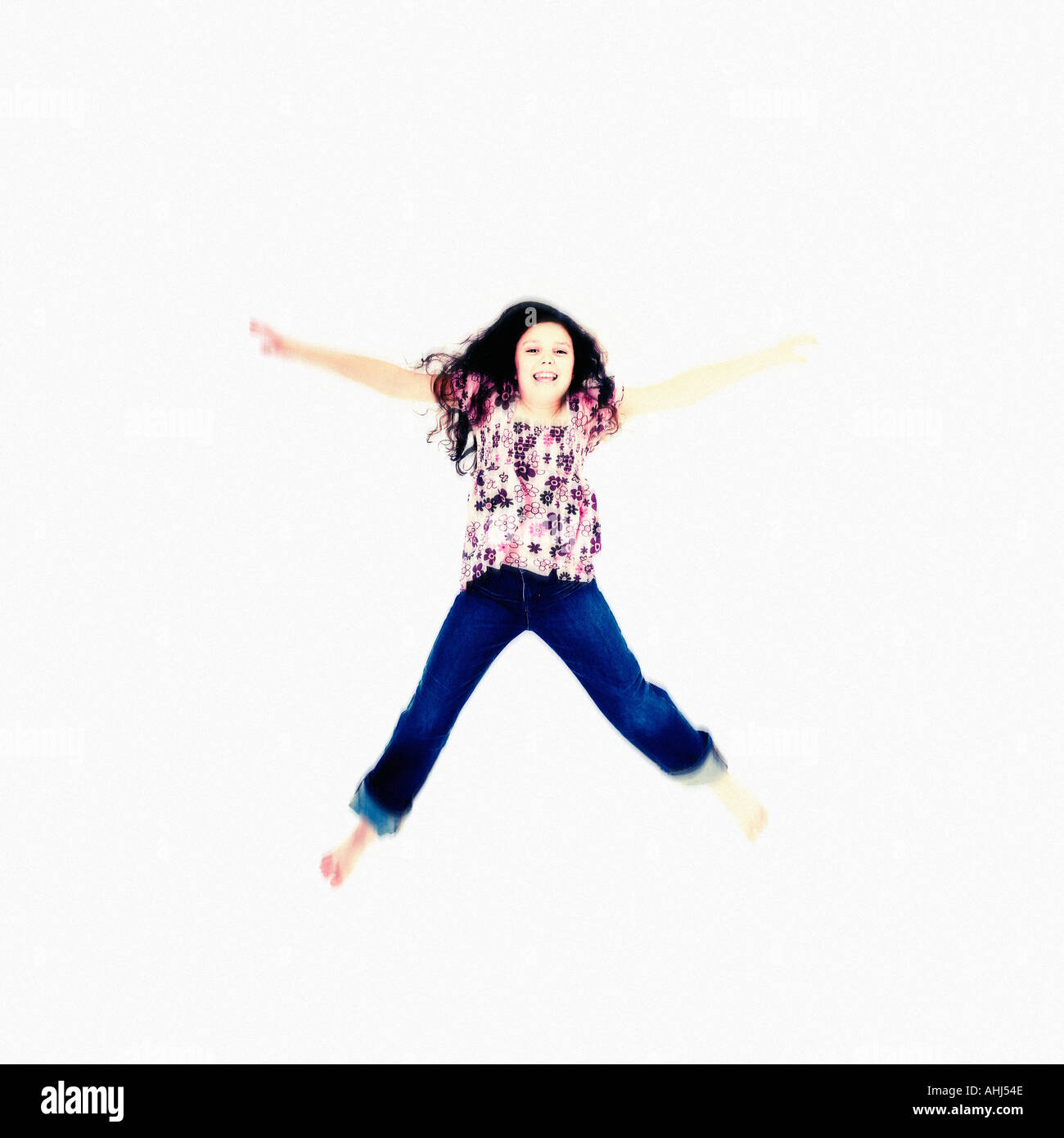 Girl doing star jump in air against white background Stock Photo - Alamy