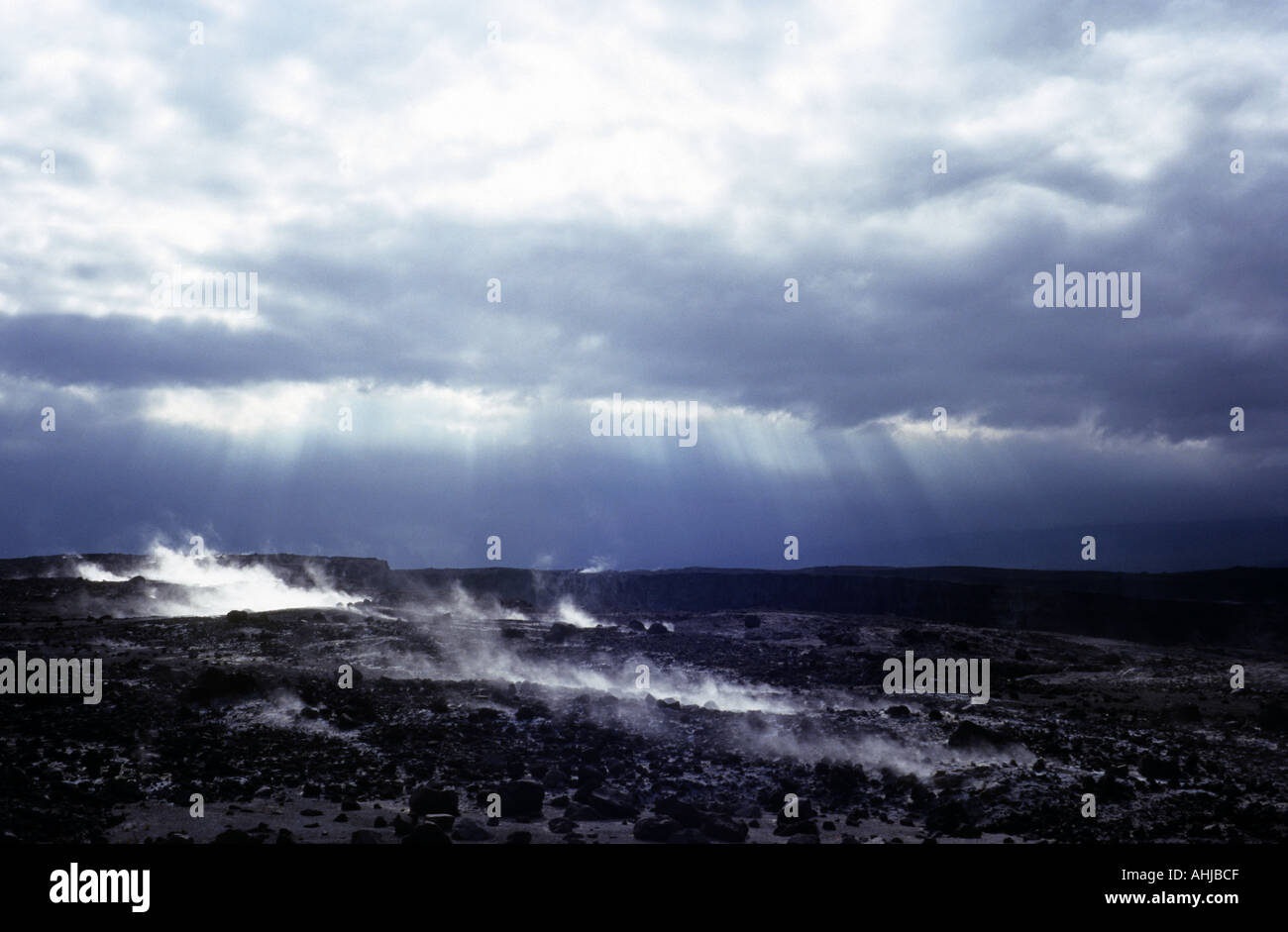 Steam venting from barren volcanic landscape strewn with black lava ...