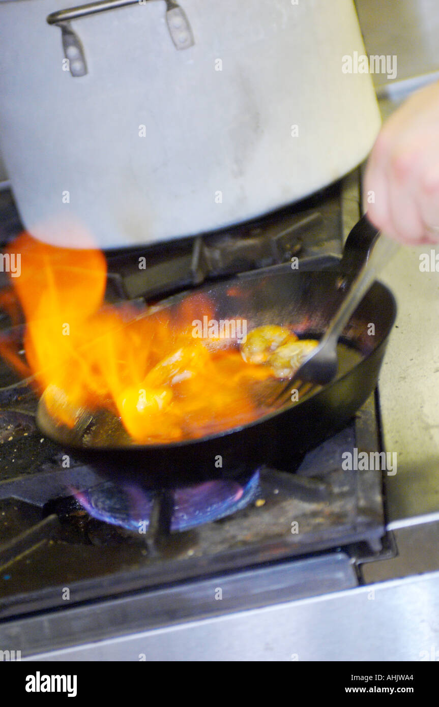 Frying pan on a gas stove with dramatic flames from flambéing with the ...