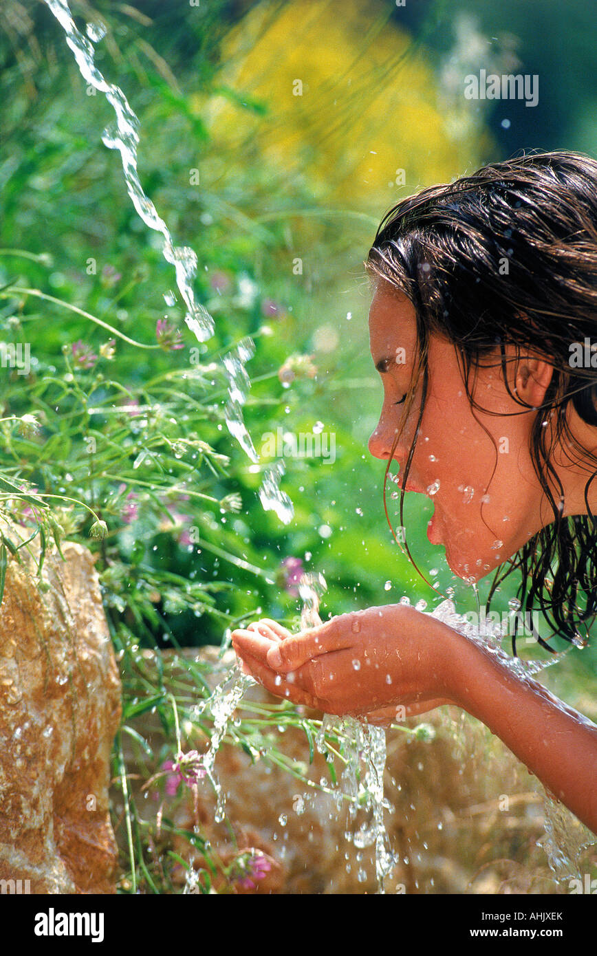 young woman refreshing her face and drinking from spring water Stock ...