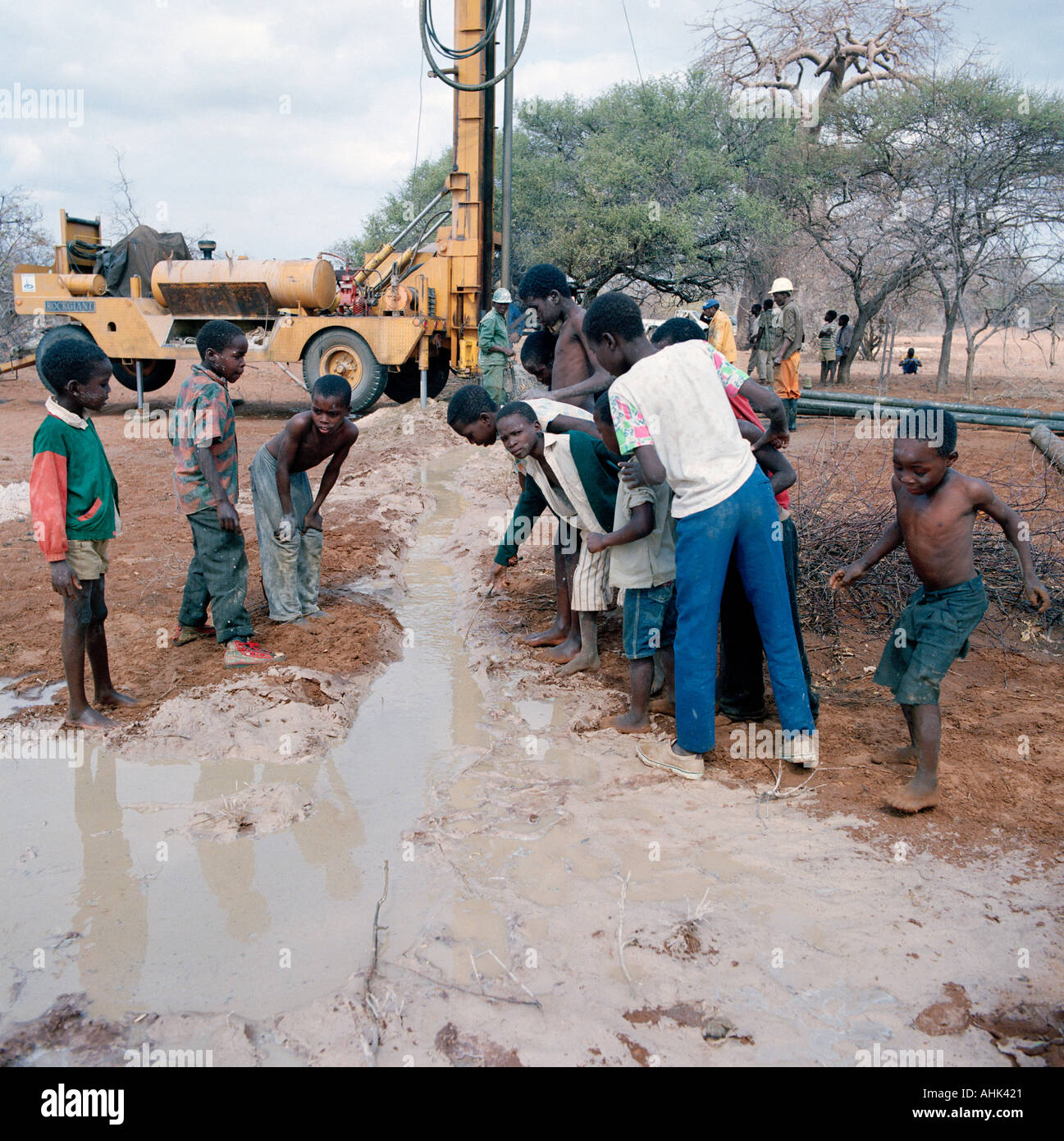 Children watch excitedly as a drilling rig strikes safe drinking water ...