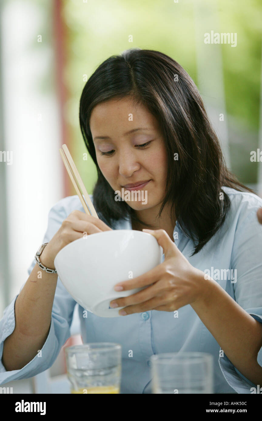 Asian woman eating using chopsticks Stock Photo - Alamy