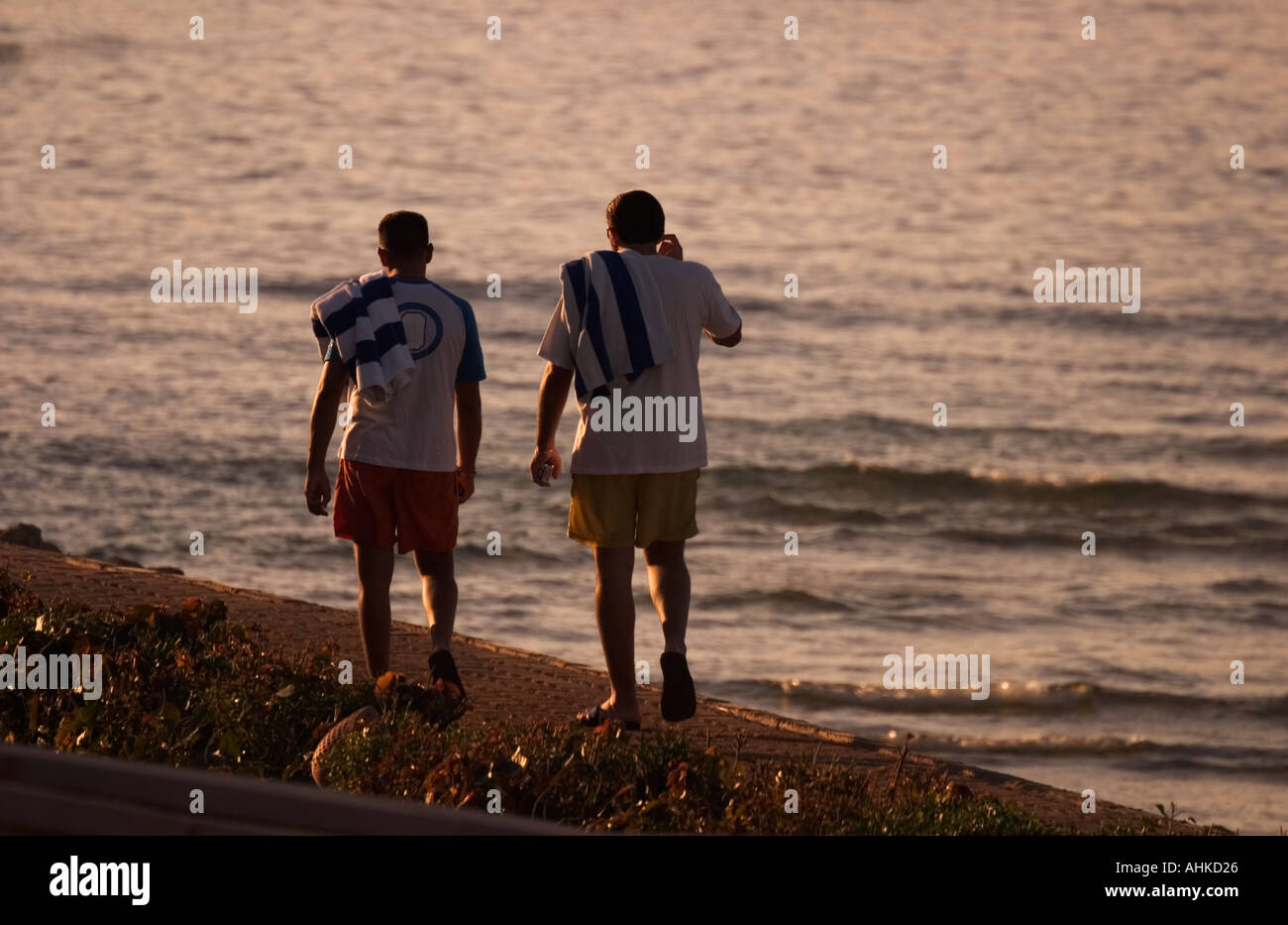 Two Men Walking along Seafront at Sunset Stock Photo - Alamy