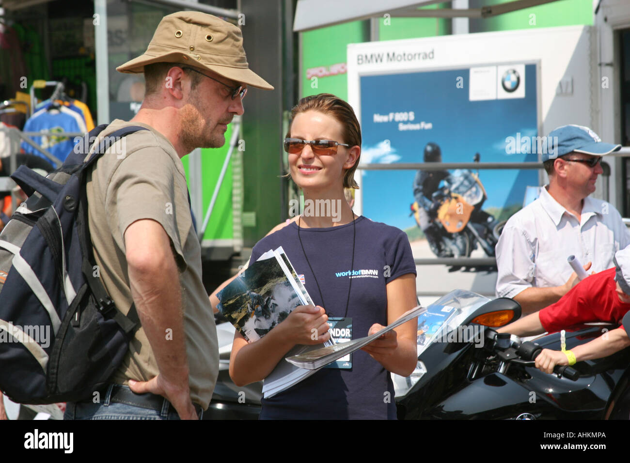 Promotions girl talking to visitor to show and giving out leaflets ...