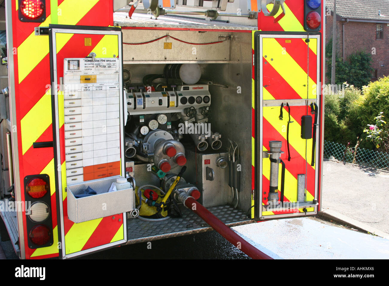 Rear of fire tender with doors open showing pump and hose connections ...