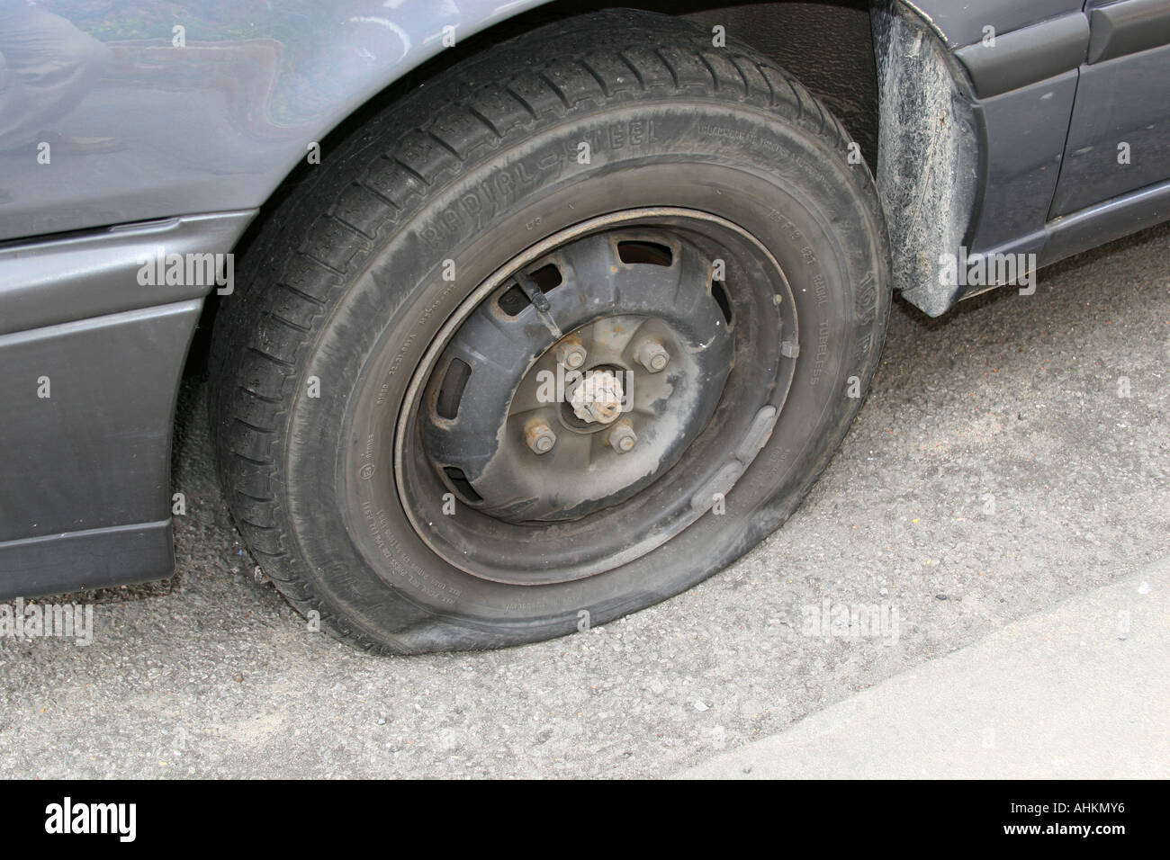 Flat tire on car parked at side of road Stock Photo - Alamy