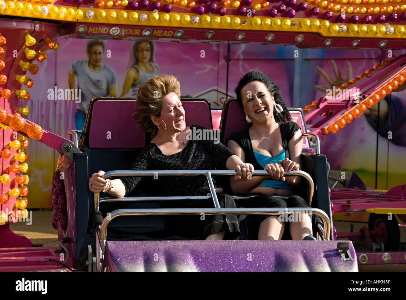 Two women enjoying a funfair ride Stock Photo - Alamy