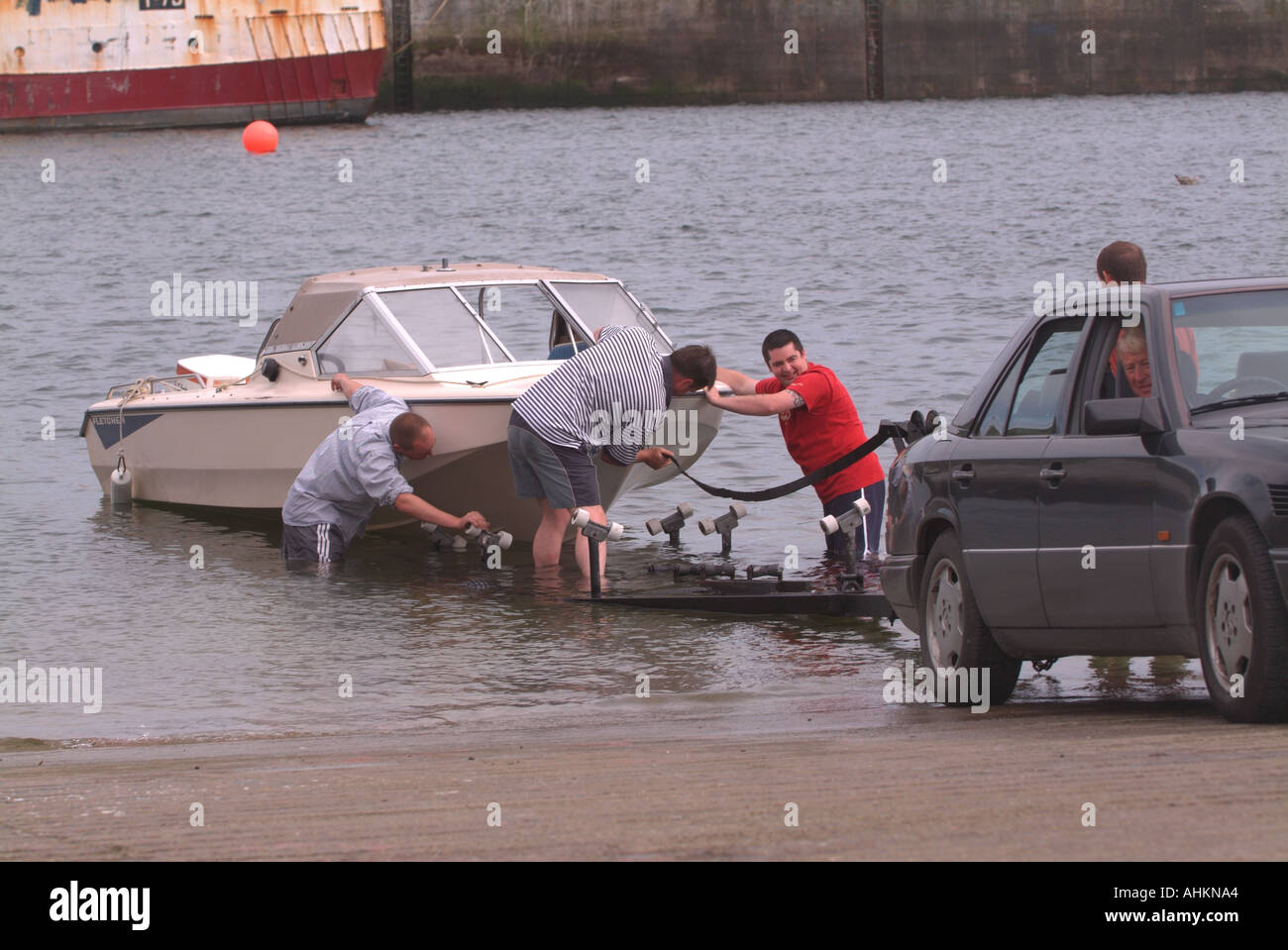 men taking motor boat out of water at a launch in dingle harbour county ...