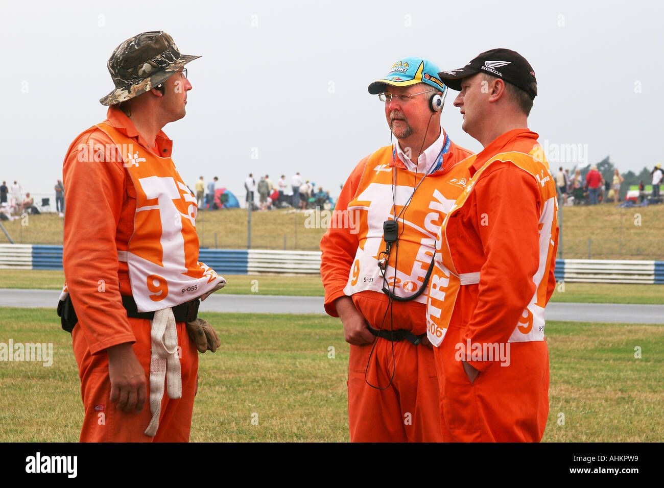 Safety marshals in orange protective suits at a motorcycle racing ...
