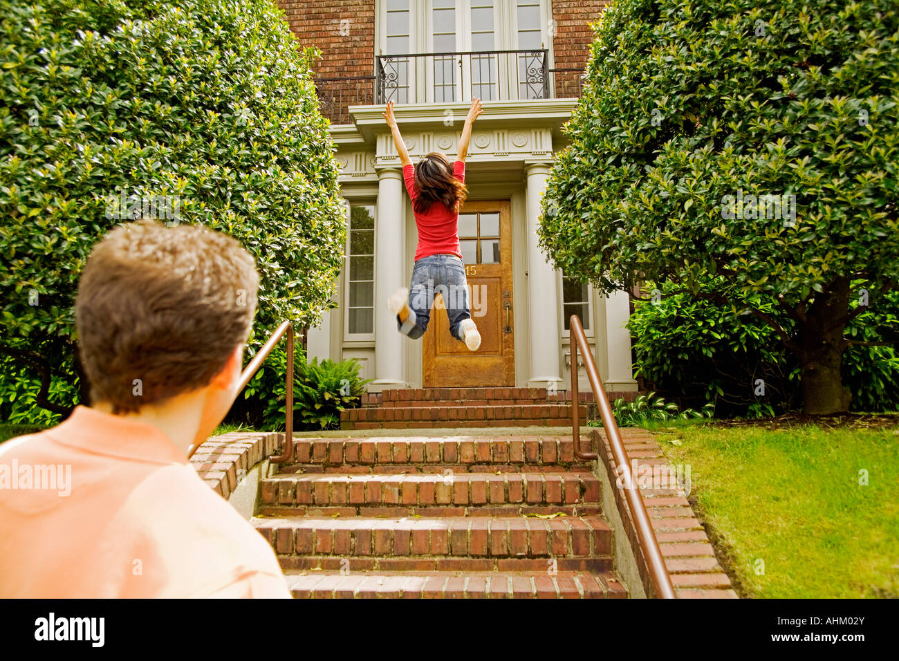 Woman jumping in front of house Stock Photo - Alamy