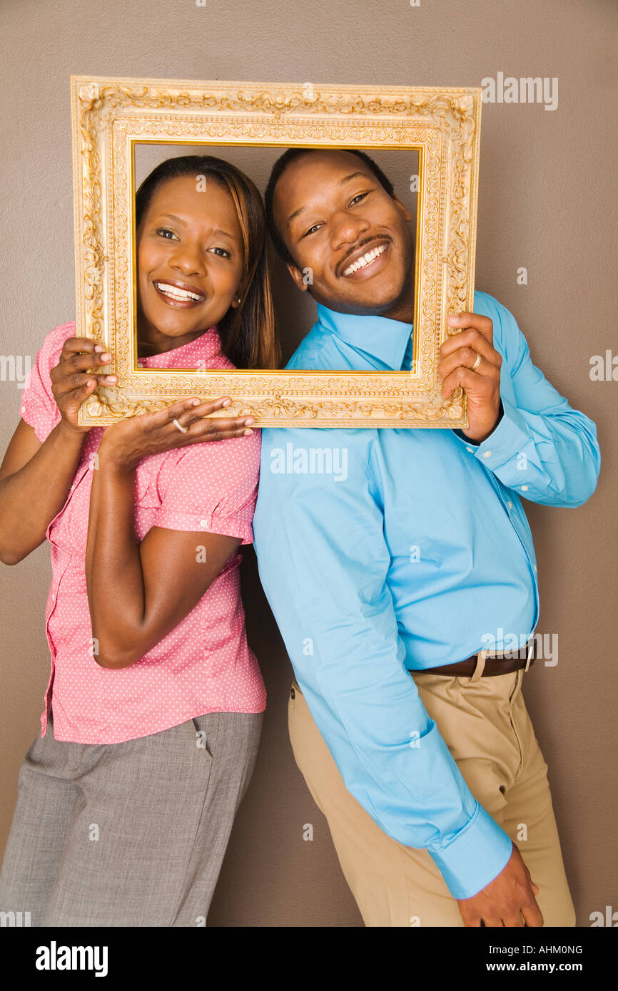African couple looking through picture frame Stock Photo - Alamy