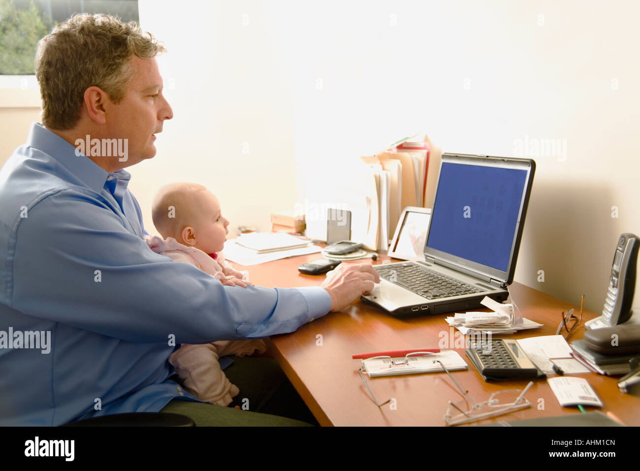 Businessman working with baby on lap Stock Photo - Alamy