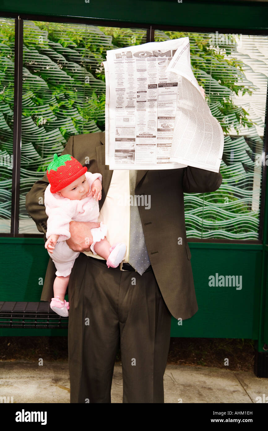 Businessman holding baby at bus stop Stock Photo - Alamy