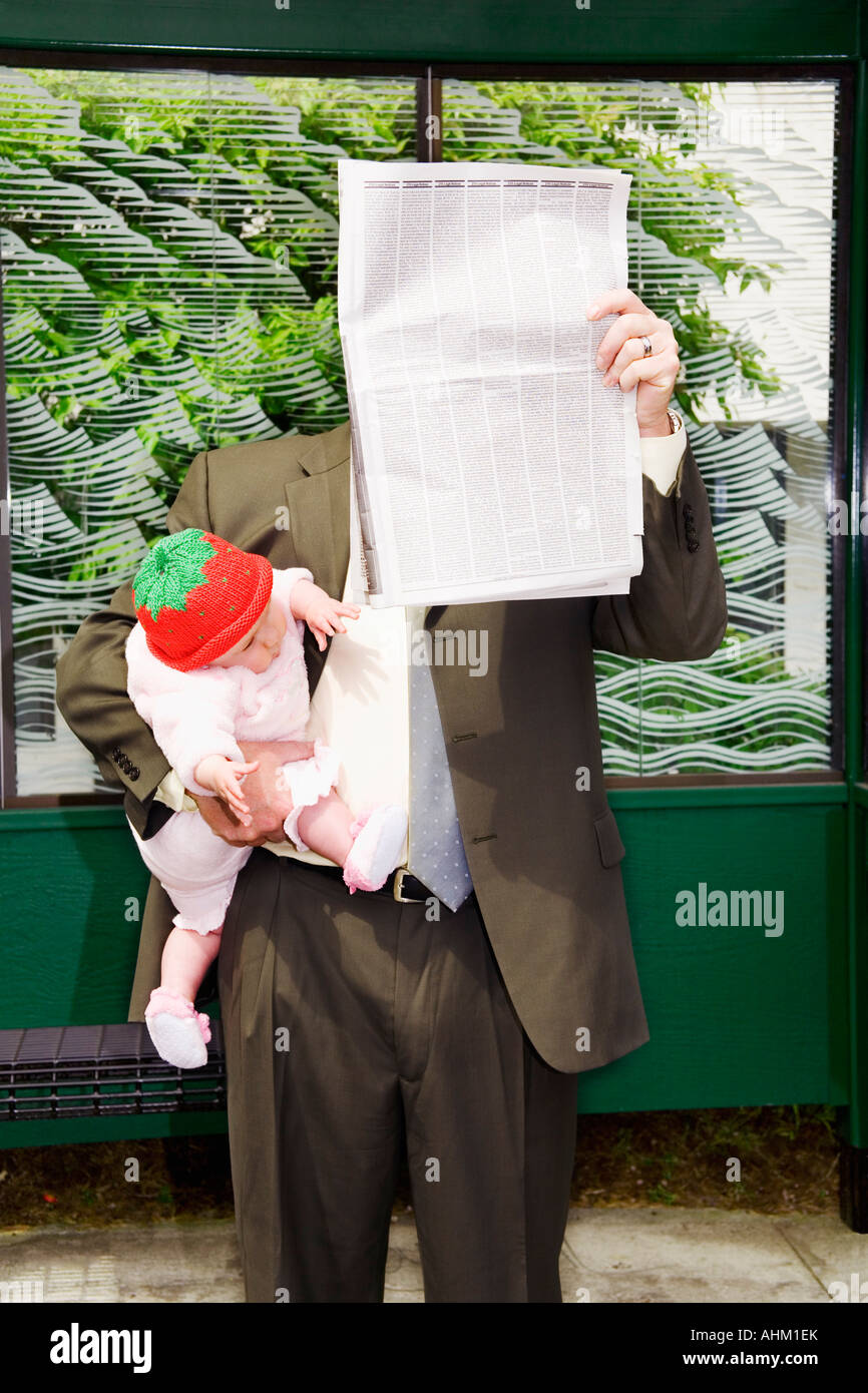 Businessman holding baby at bus stop Stock Photo - Alamy