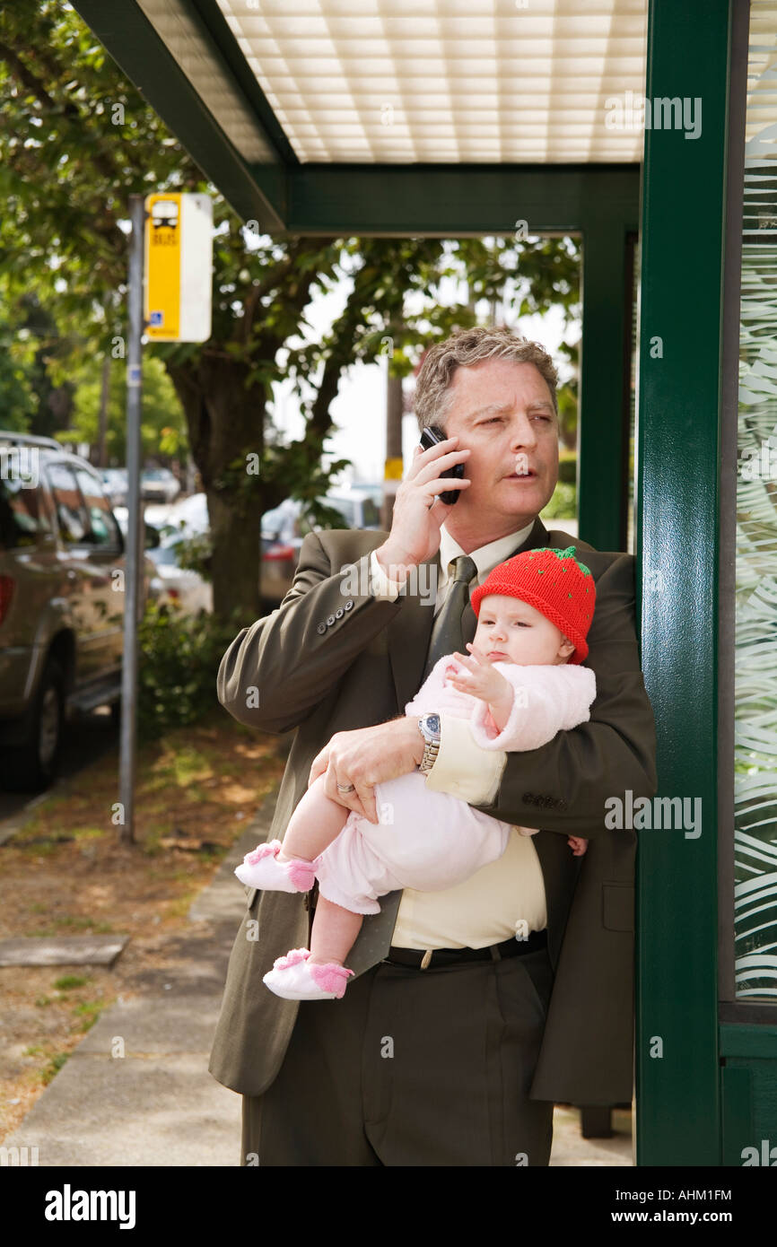 Businessman holding baby at bus stop Stock Photo - Alamy