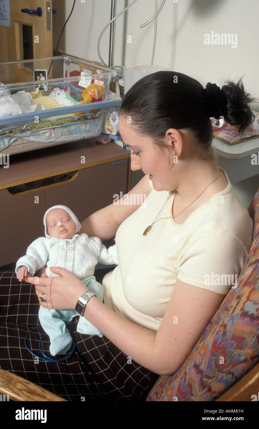 young mum holding her little premature baby in special care baby unit ...